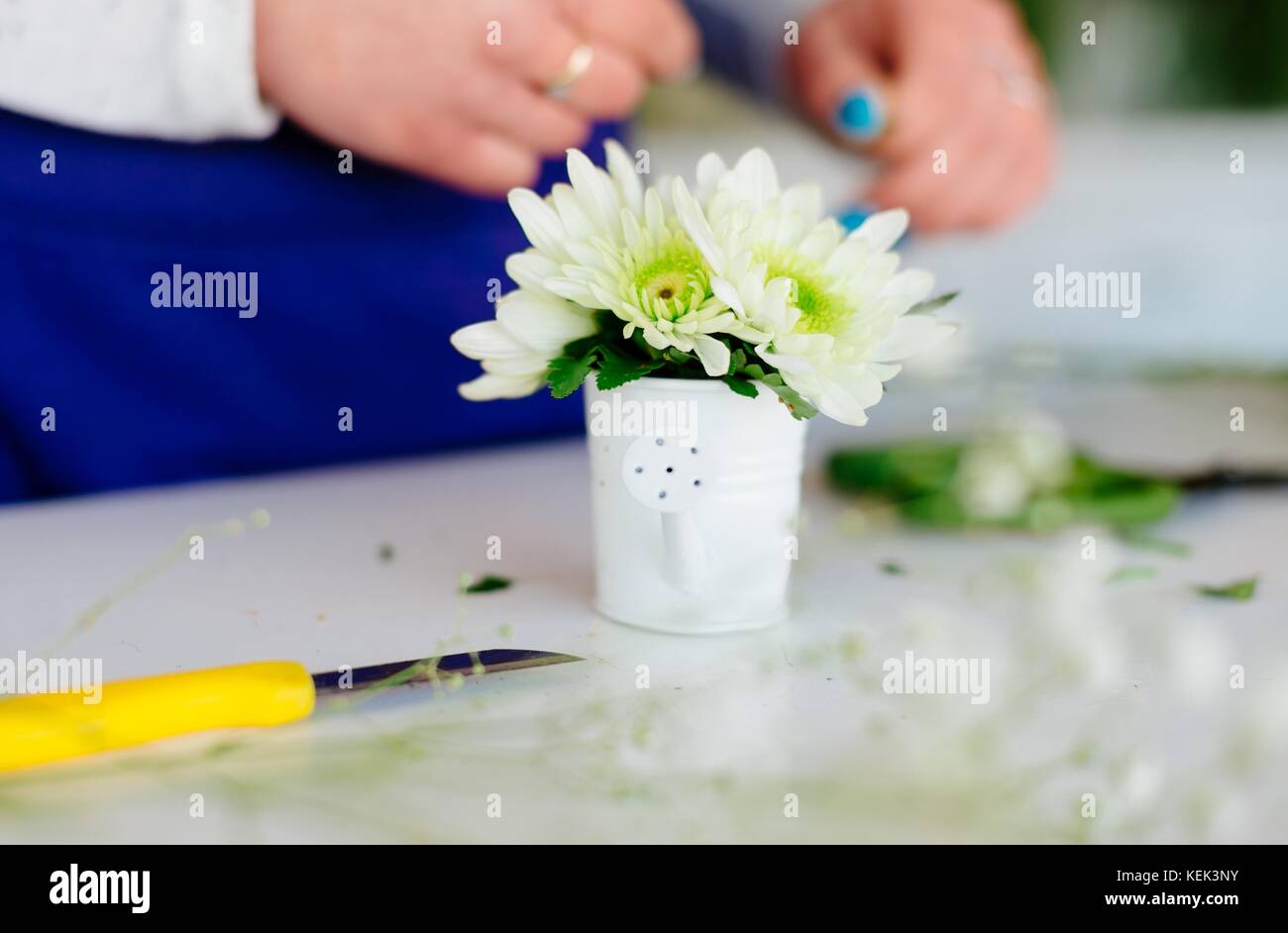 Florist woman making a miniature flower composition in small watering ...