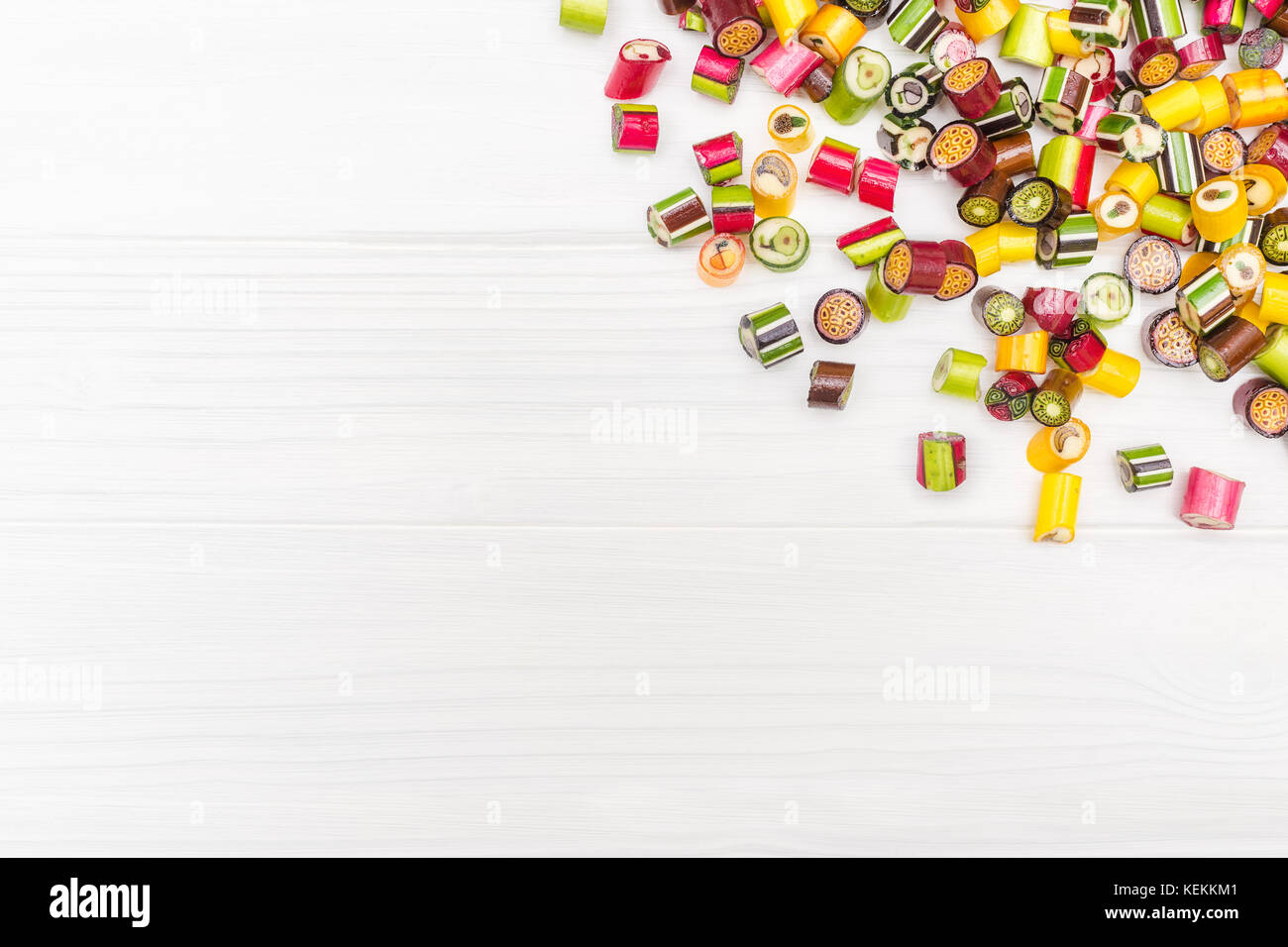 A corner frame made of colored caramel candies on white wooden ...