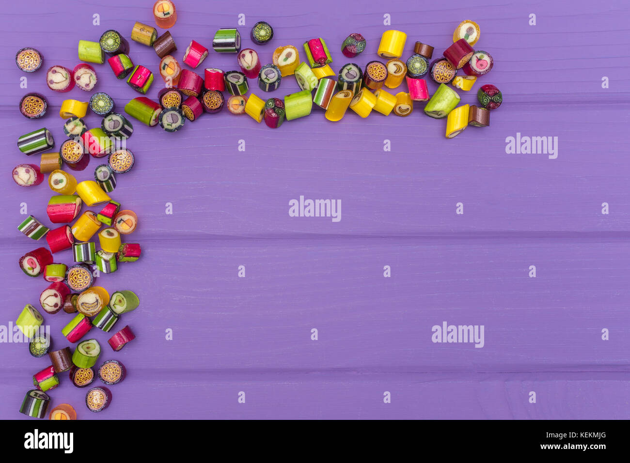 A corner frame made of colored caramel candies on wooden purple ...