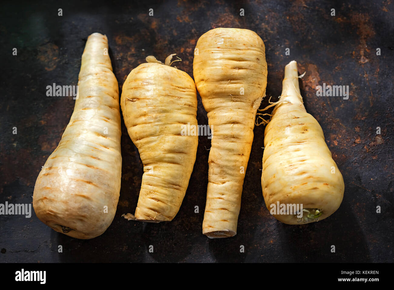 Raw parsnip roots on black surface Stock Photo - Alamy