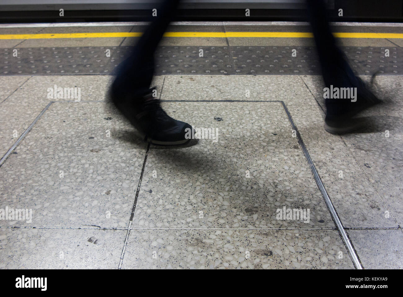 Blurred feet walking quickly on a London underground station platform ...