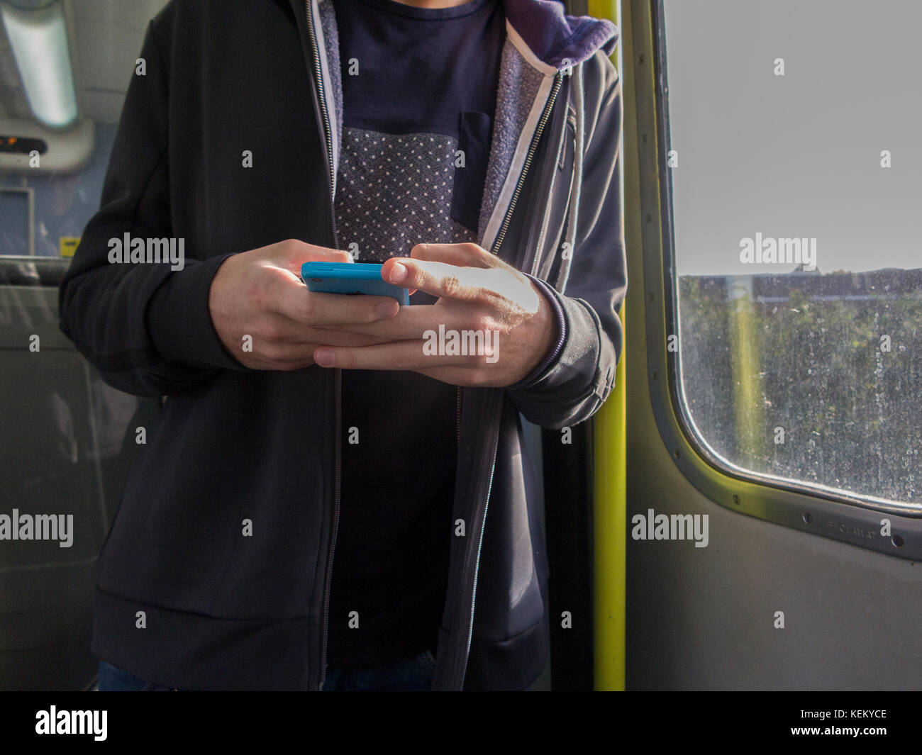 A teenager uses his cellphone on a train Stock Photo - Alamy