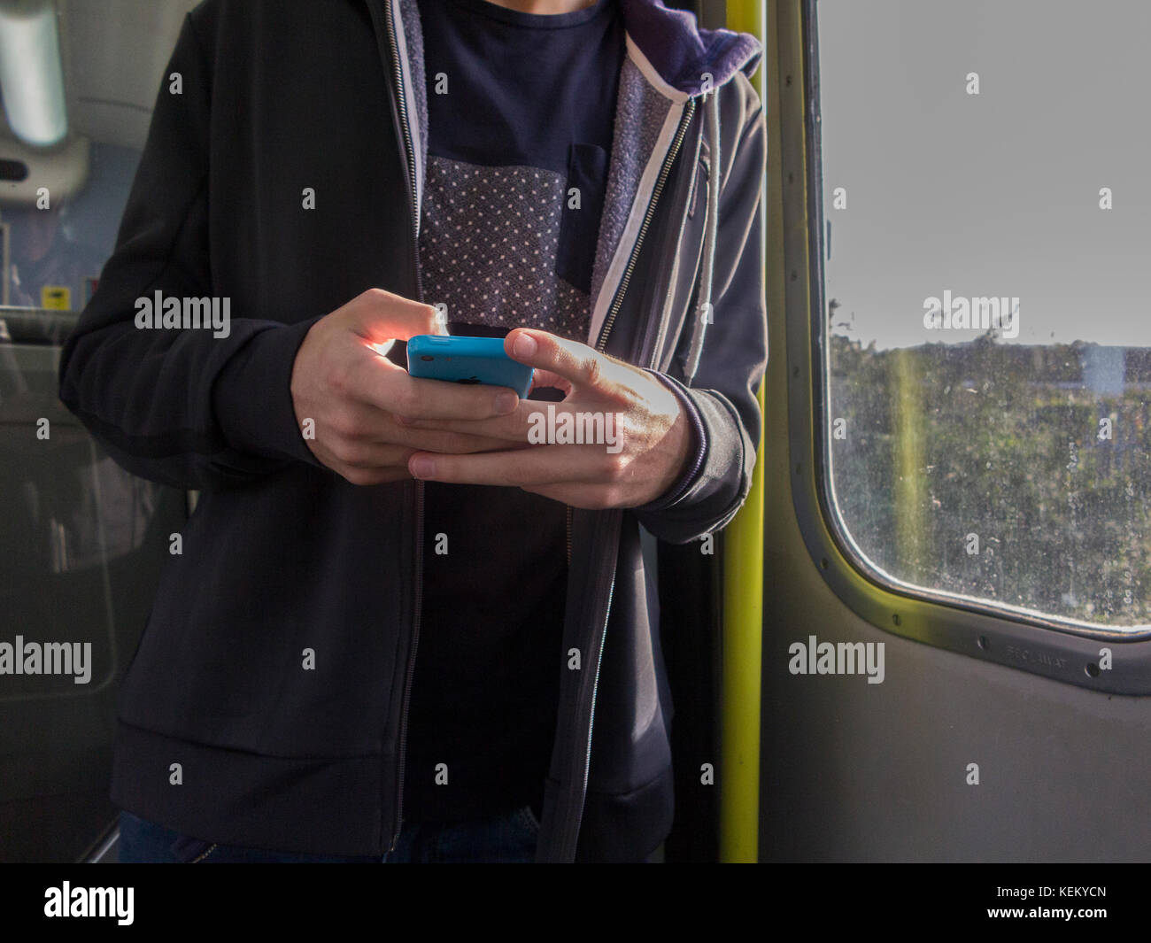 A teenager uses his cellphone on a train Stock Photo - Alamy
