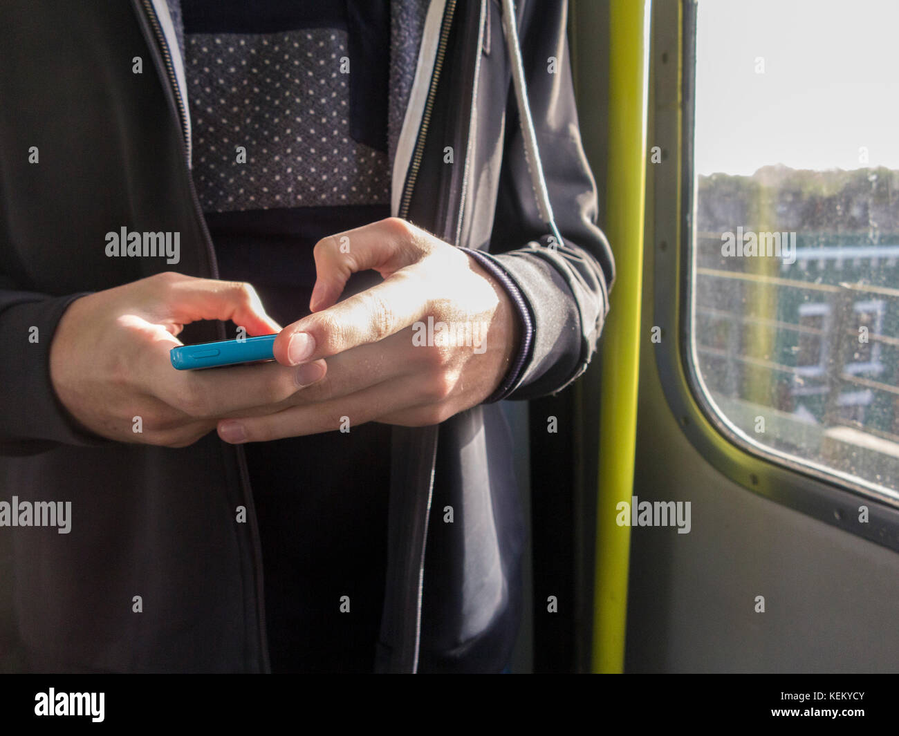 A teenager uses his cellphone on a train Stock Photo - Alamy
