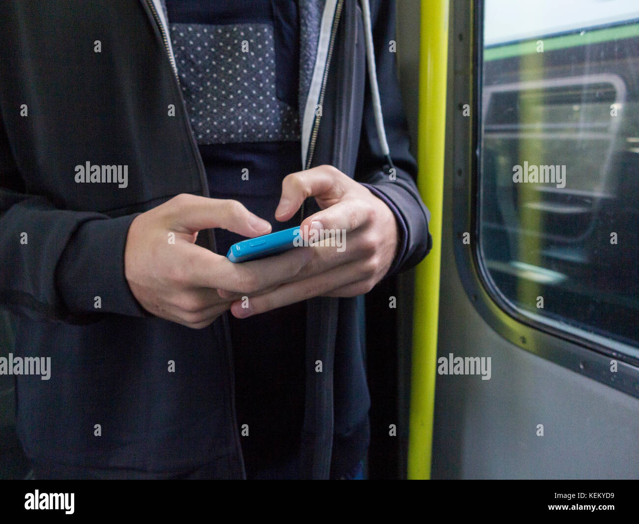 A teenager uses his cellphone on a train Stock Photo - Alamy