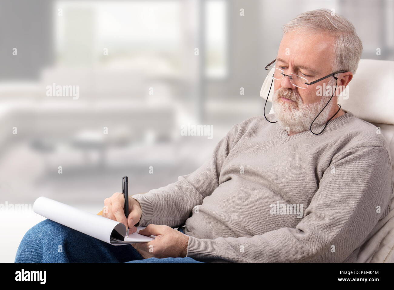 Old man making a shopping list with a pen on paper for holidays Stock ...