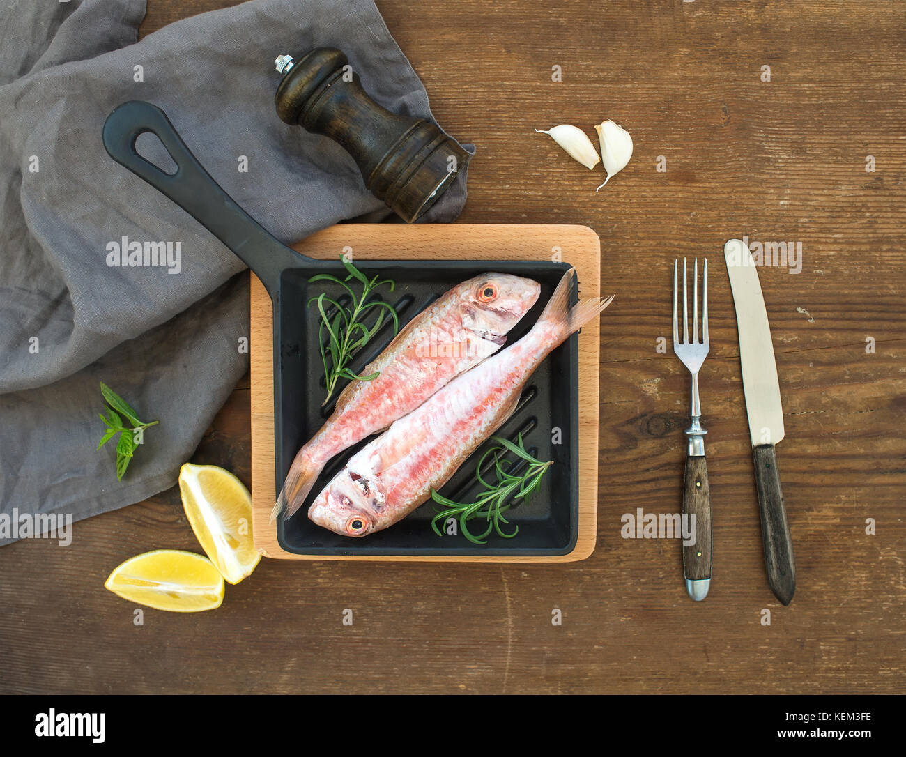 Raw uncooked Red Mullet fish in a cooking pan with rosemary, lemon and ...