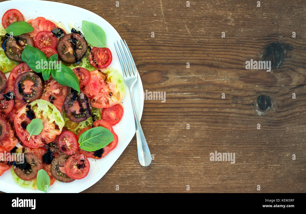 Ripe village heirloom tomato salad with olive oil and basil over rustic ...