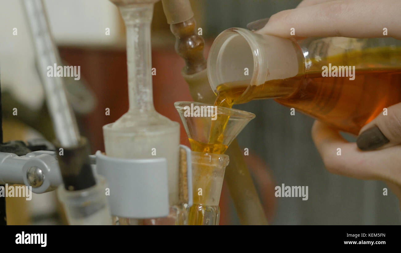 Chemical glass with green fluid poured into a red one among the funnels ...