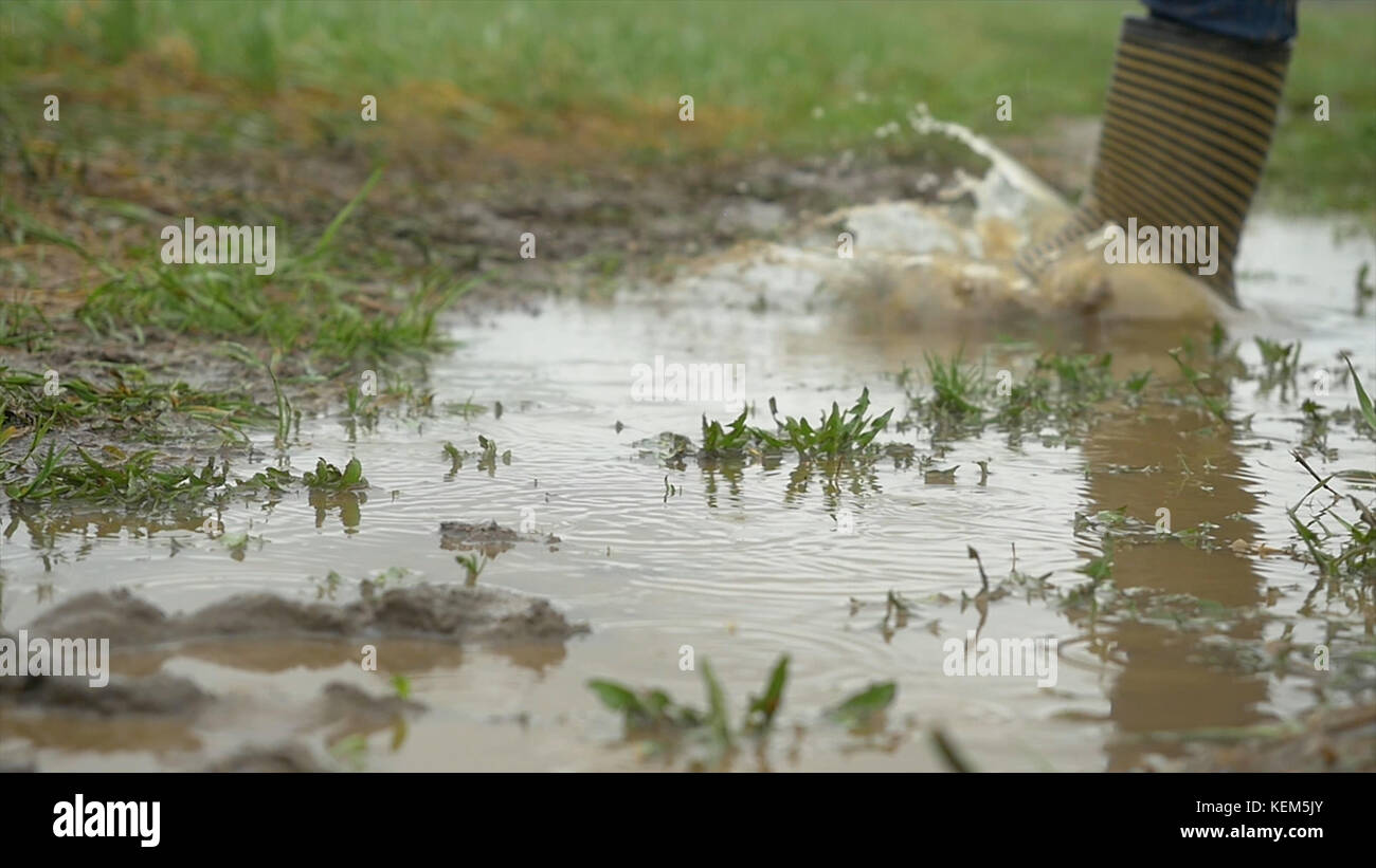 Person with pink boots and blue umbrella splashing in the puddle. girl ...