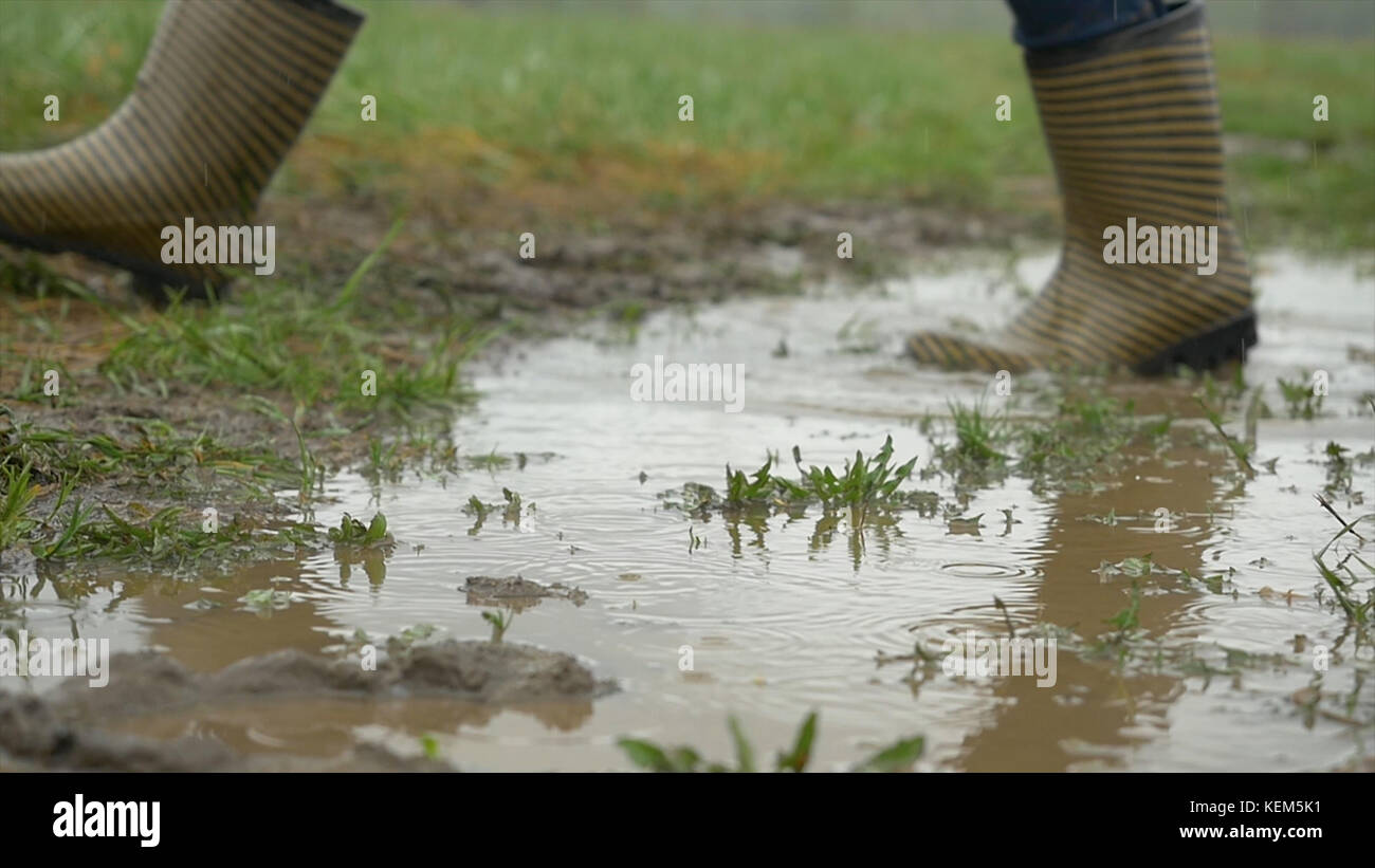 Person with pink boots and blue umbrella splashing in the puddle. girl ...