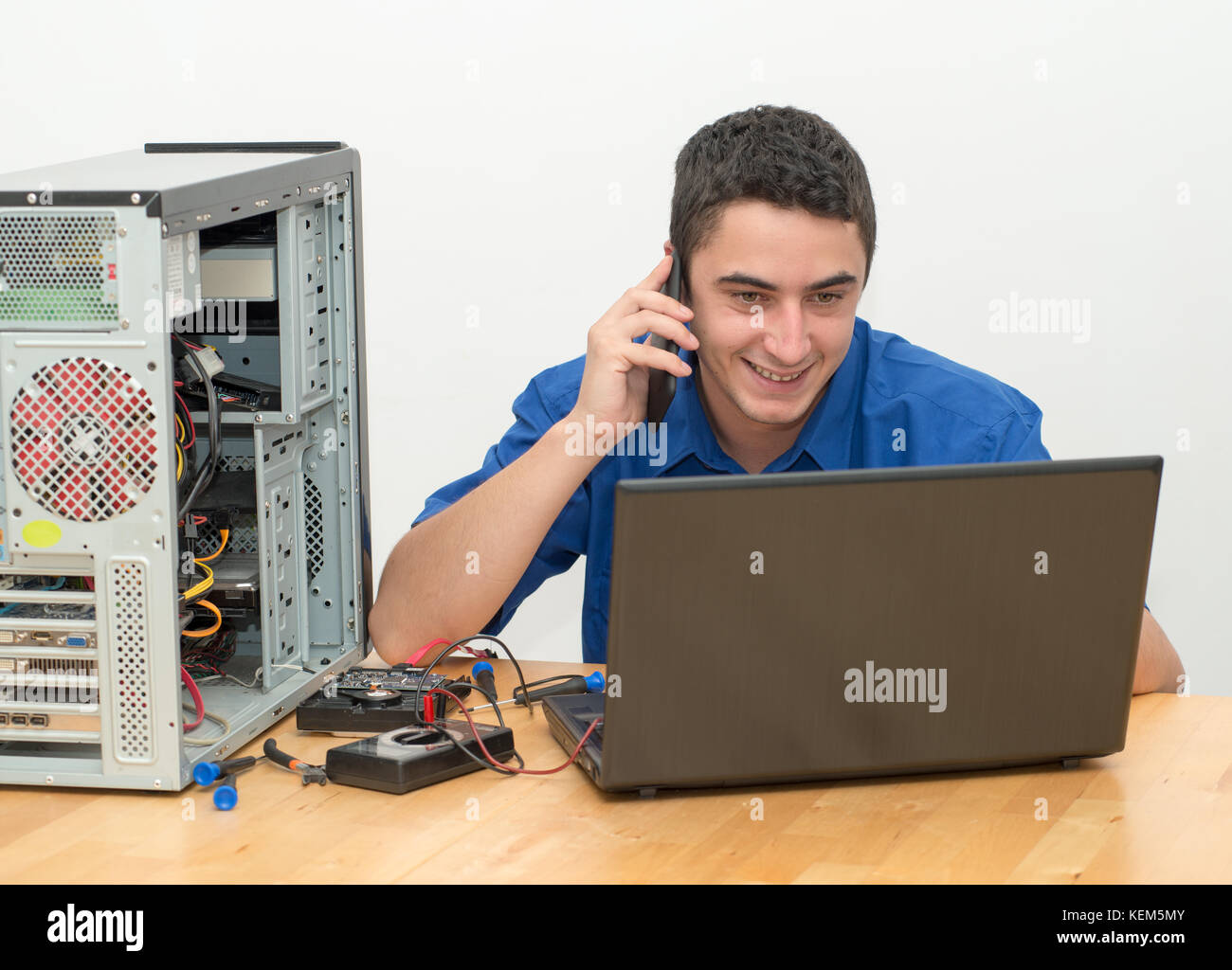 a young man technician working on broken computer and call the customer ...