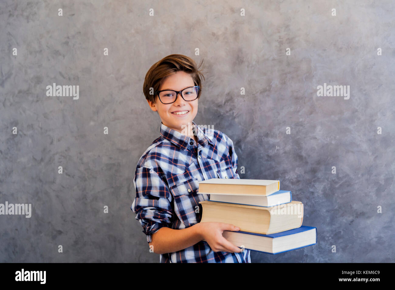 Cute teenage school boy holding books against wall Stock Photo - Alamy