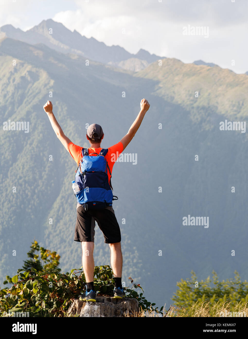 Image from back of guy with backpack with hands up against background ...