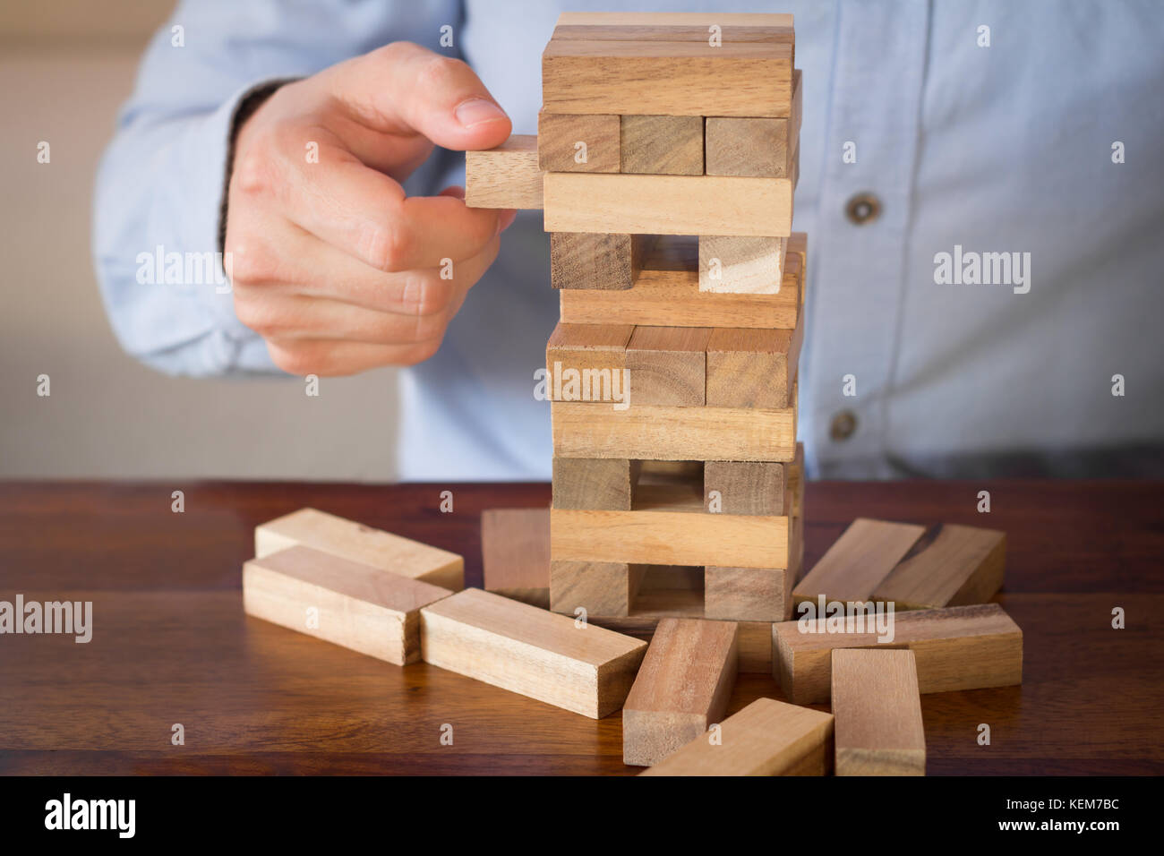hand of businessman pulling out or placing wood block on the tower ...