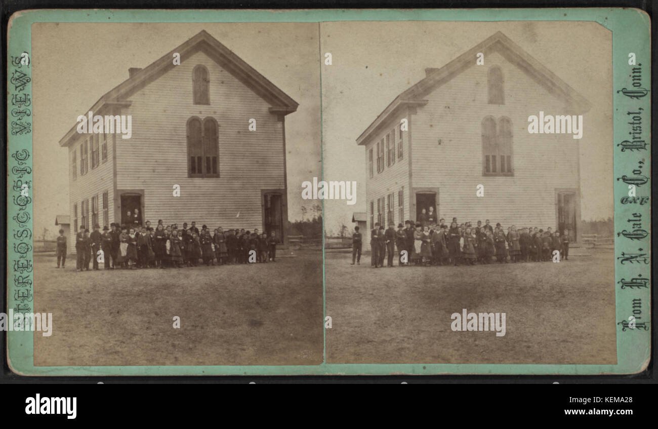 View of a two story wood frame school house with students and teachers ...