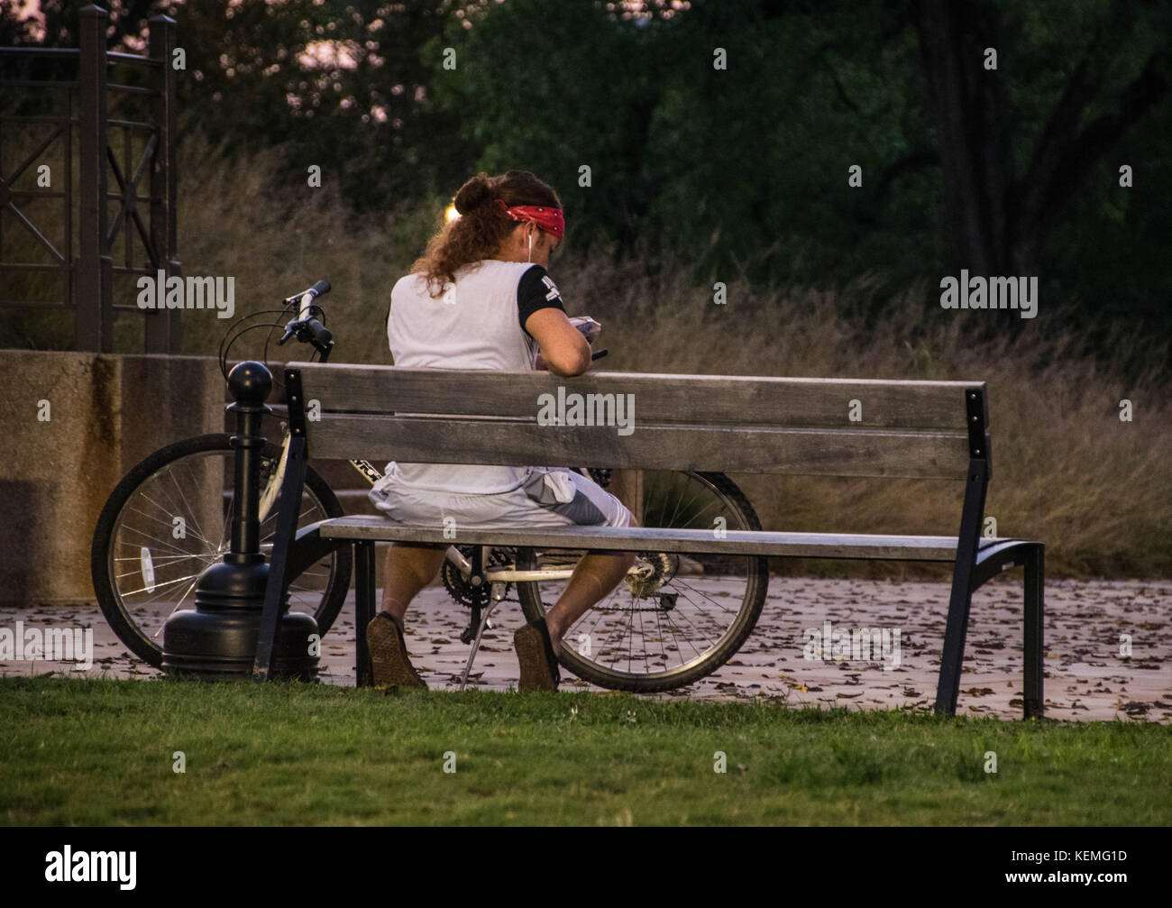 Biker taking a break at park bench Stock Photo - Alamy