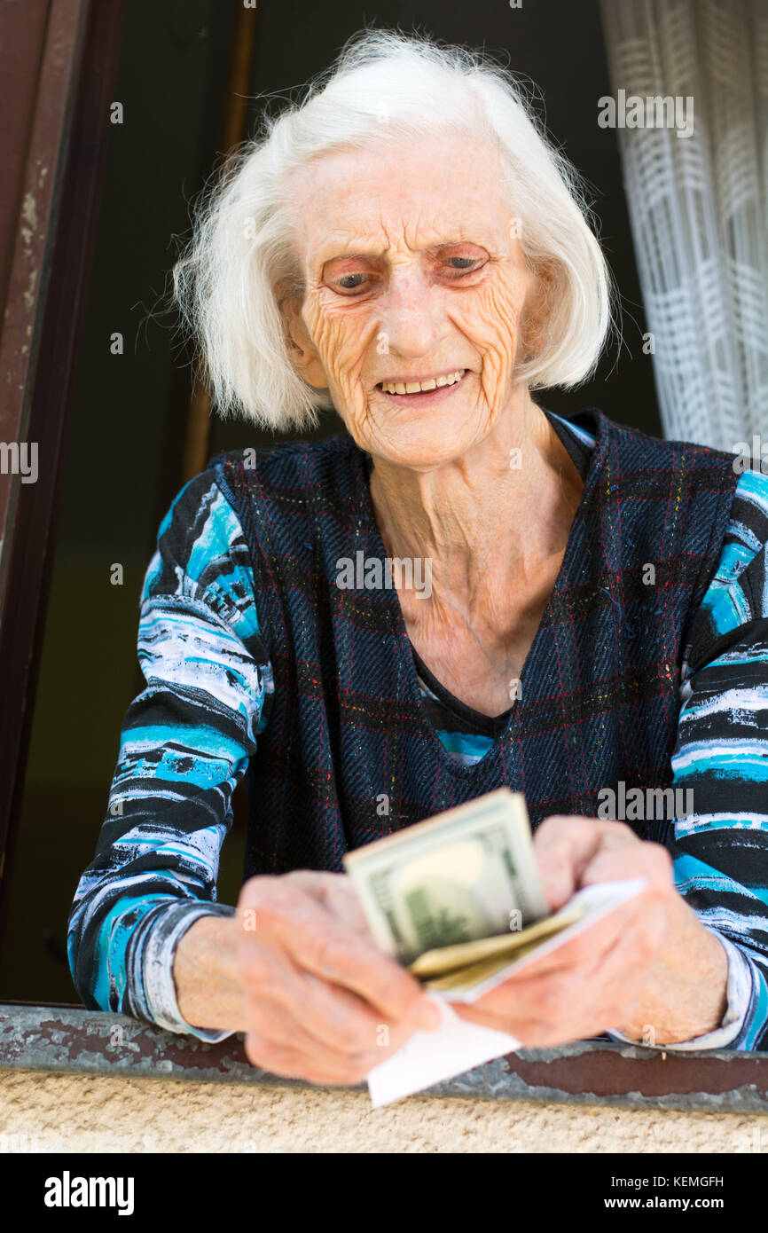 Grandma counting retirement money at home on the window at home Stock ...