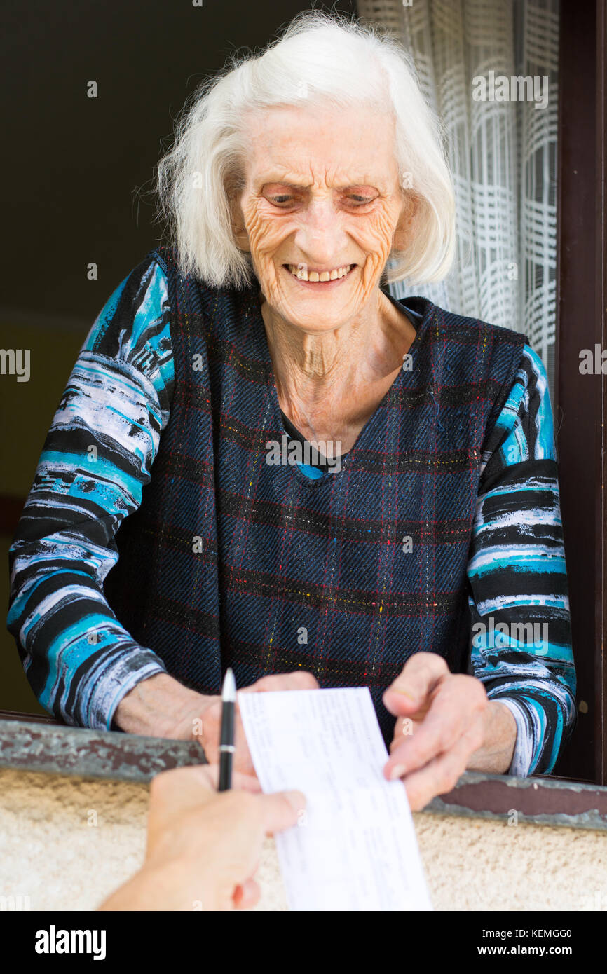 Senior woman receiving retirement check on the window at home Stock ...