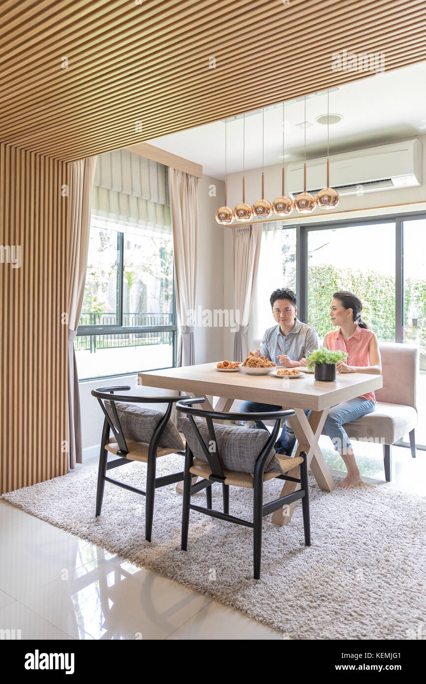 Young Asian Couples eating fried chicken together in living room of ...
