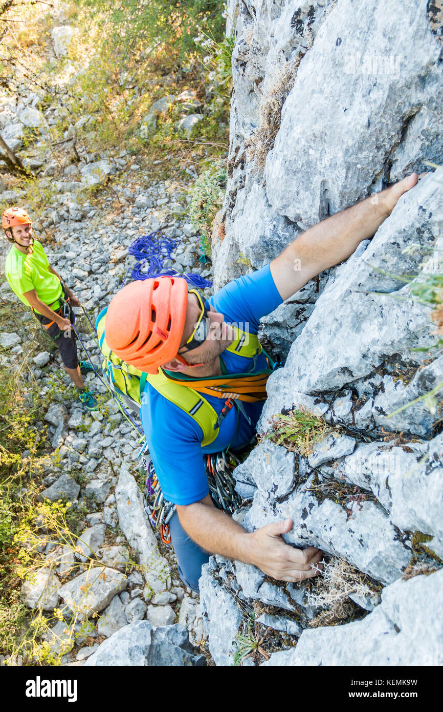 From below two alpinists men climbing up on hill together Stock Photo ...