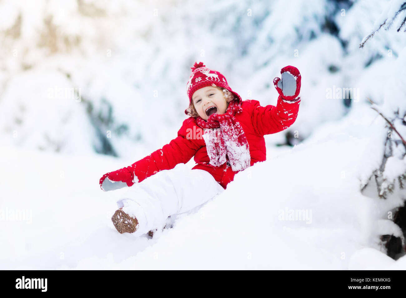Child playing with snow in winter. Little boy in colorful jacket and ...
