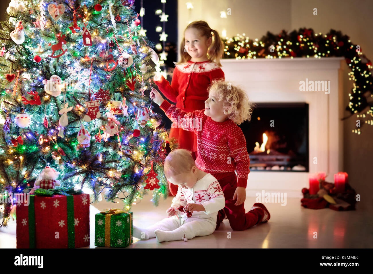Children at Christmas tree and fireplace on Xmas eve. Family with kids ...