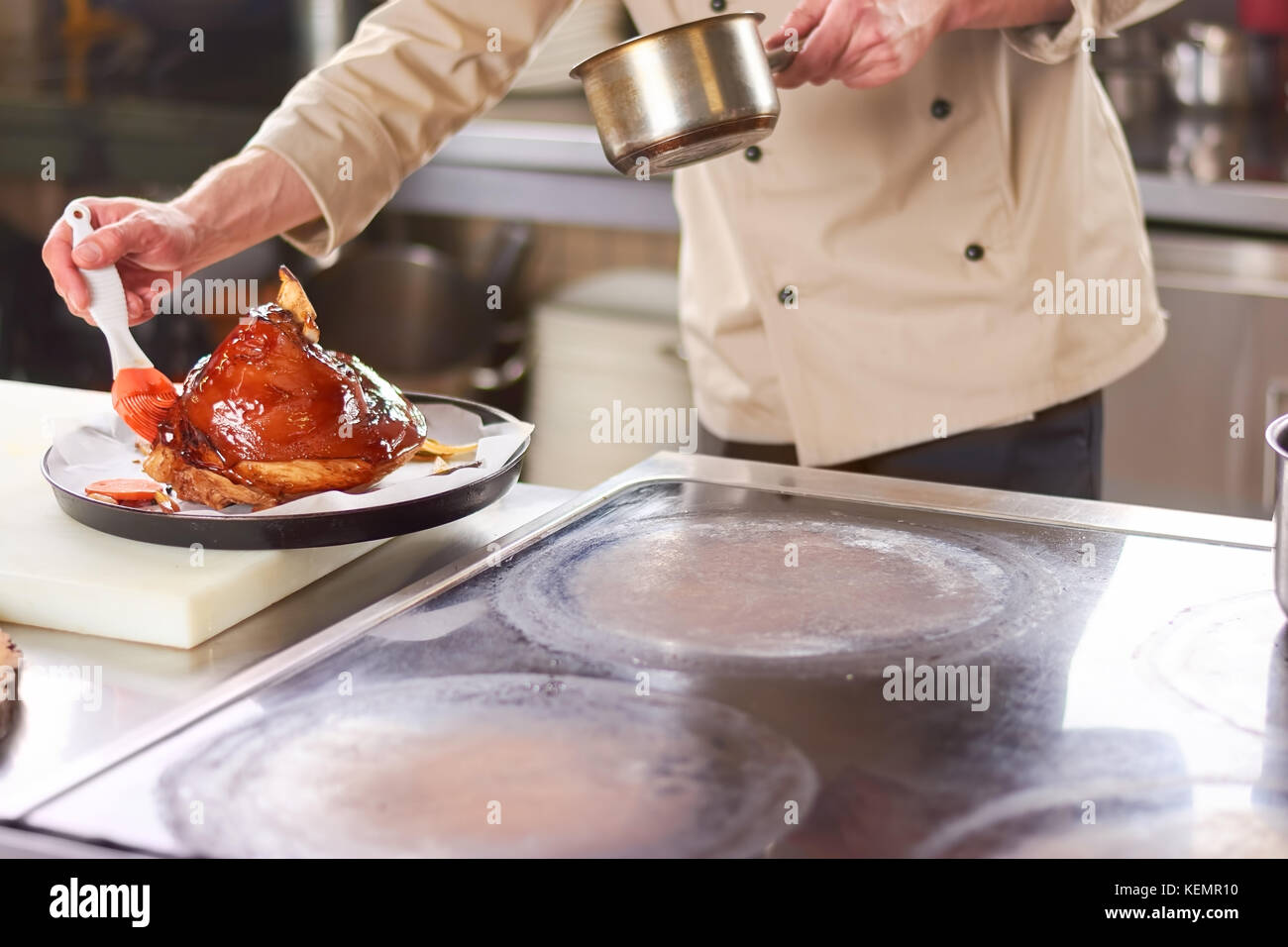 Chef processing lamb shank with sauce. Male chef at restaurant kitchen ...