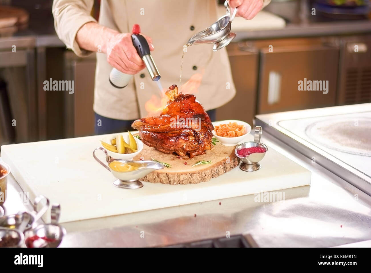 Chef burning lamb shank with torch burner. Male chef pouring lamb shank ...