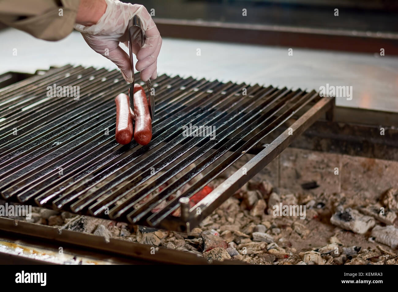 Man cooking sausage on iron grill. Chef hand putting sausages on grill ...