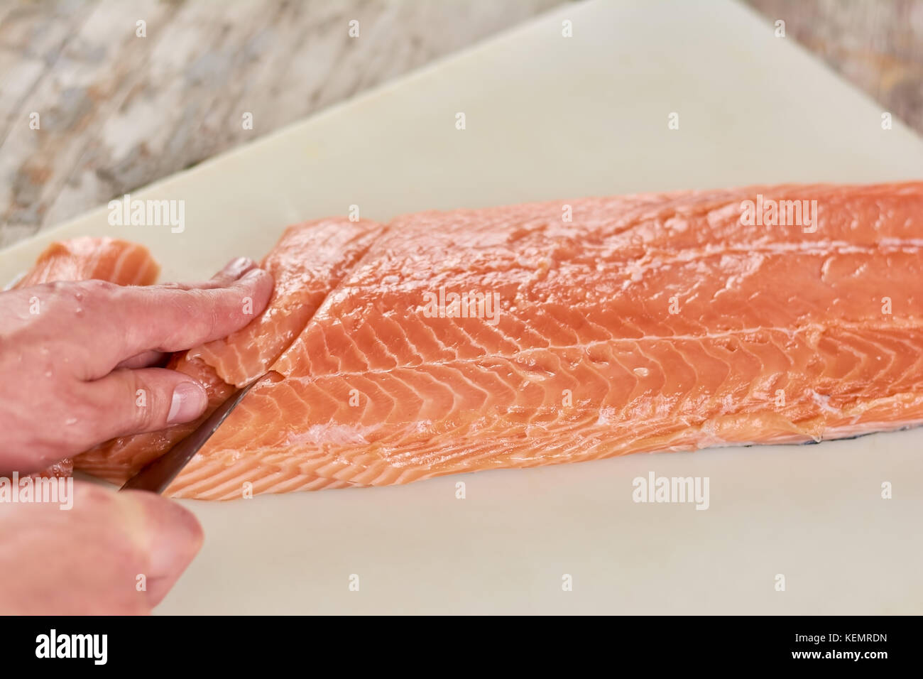 Large piece of salmon fillet. Chef hands cutting fresh salmon on white ...
