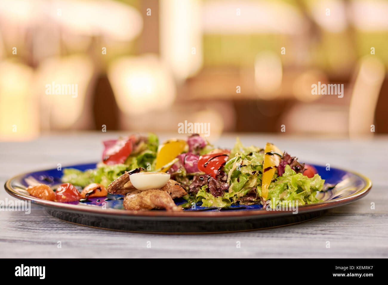 Quail with green salad on blue plate. Appetizing warm salad with quail ...