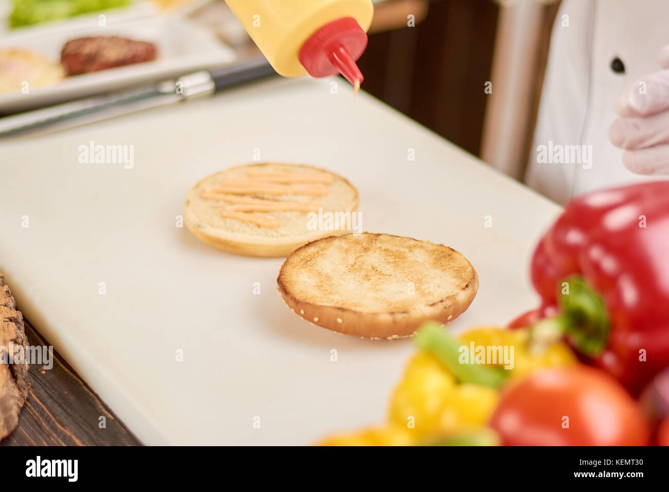 Chef cooking burger at kitchen. Chef going pour mustard on bread for ...
