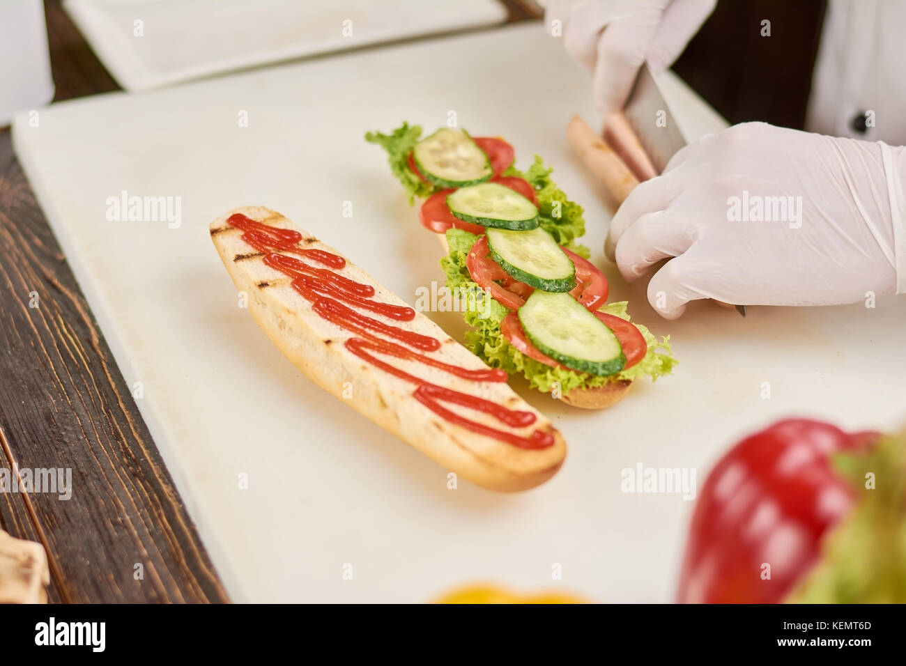 Chef hands cutting sausage to hot dog. The process of cooking long ...