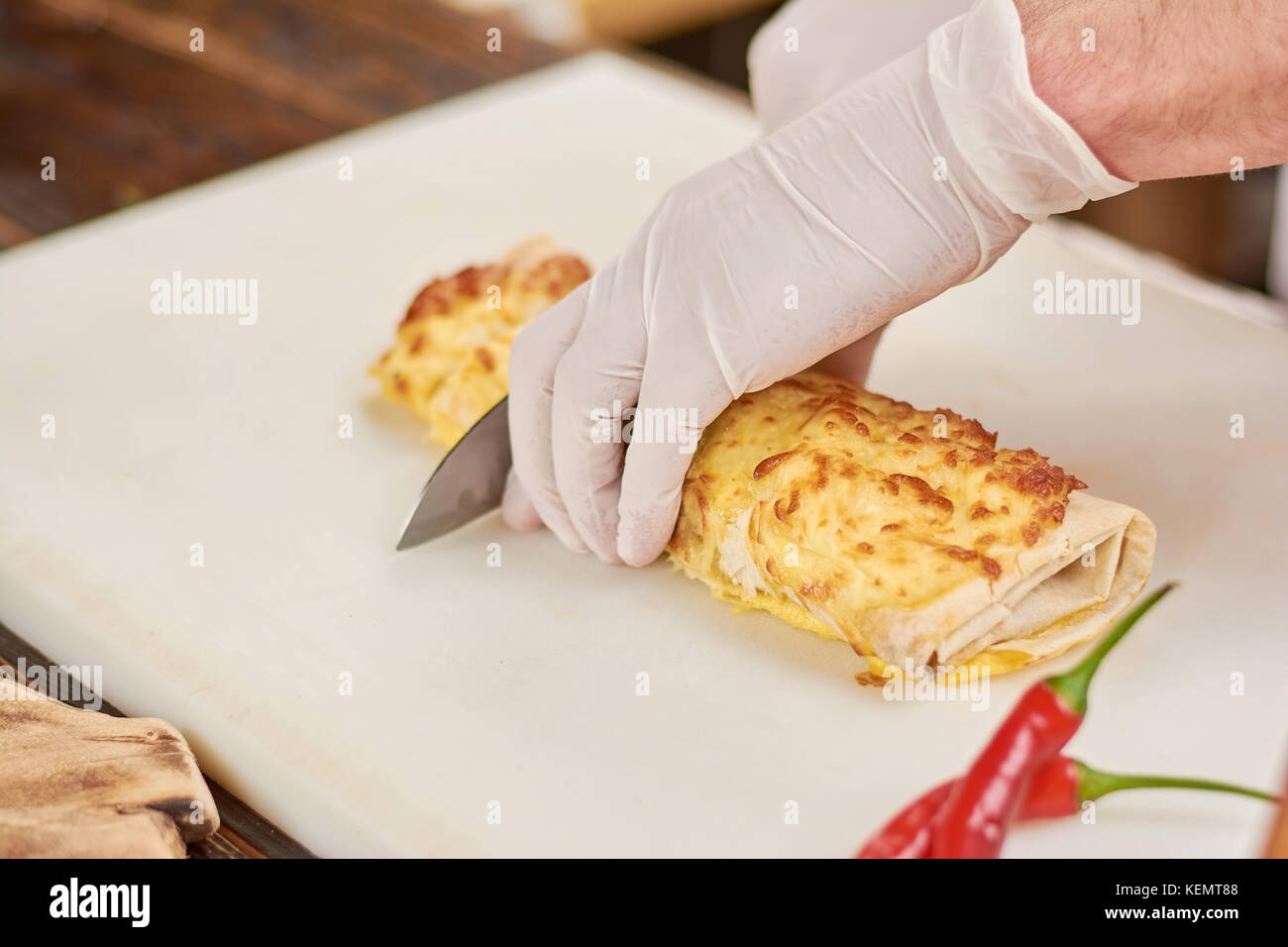 Chef hands cutting burrito on pieces. Cook chopping mexican burrito ...