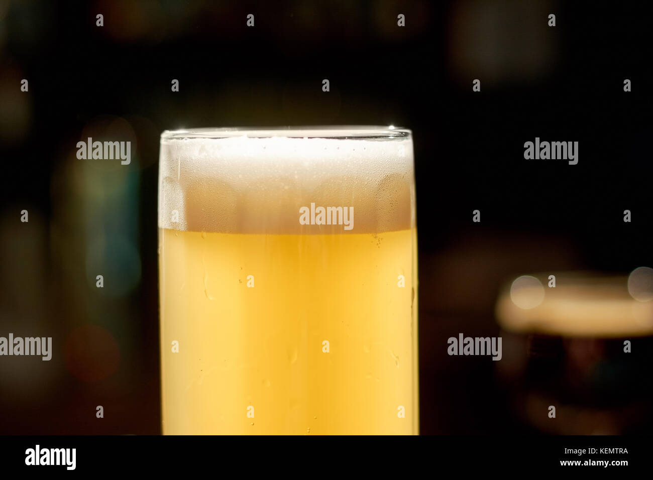 Cold lager beer on counter. Glass of fresh beverage with foam on dark ...