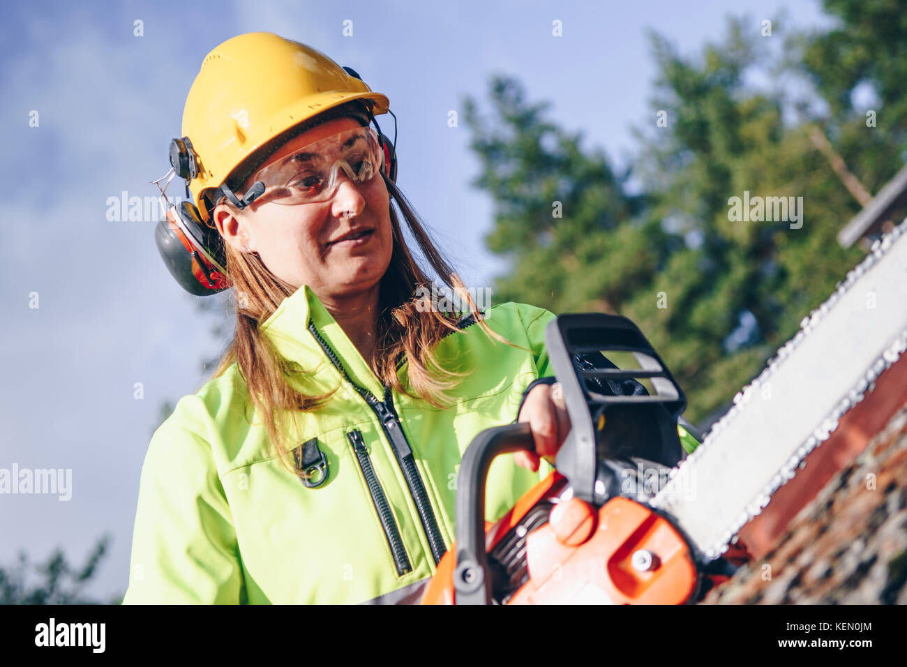 Woman operating chainsaw while wearing safety gear Stock Photo - Alamy