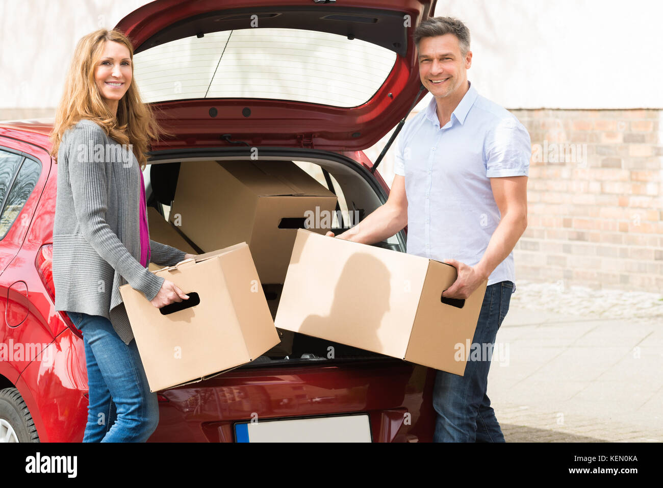 Mature Happy Couple Putting Cardboard Box In Car Trunk Stock Photo - Alamy