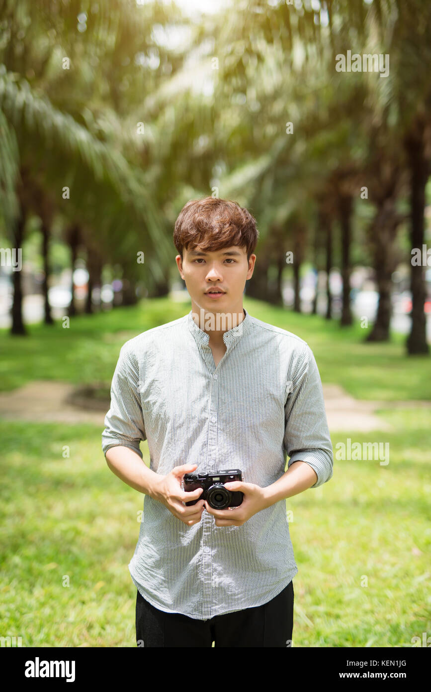 Young asian man photographer holding retro camera in park Stock Photo ...