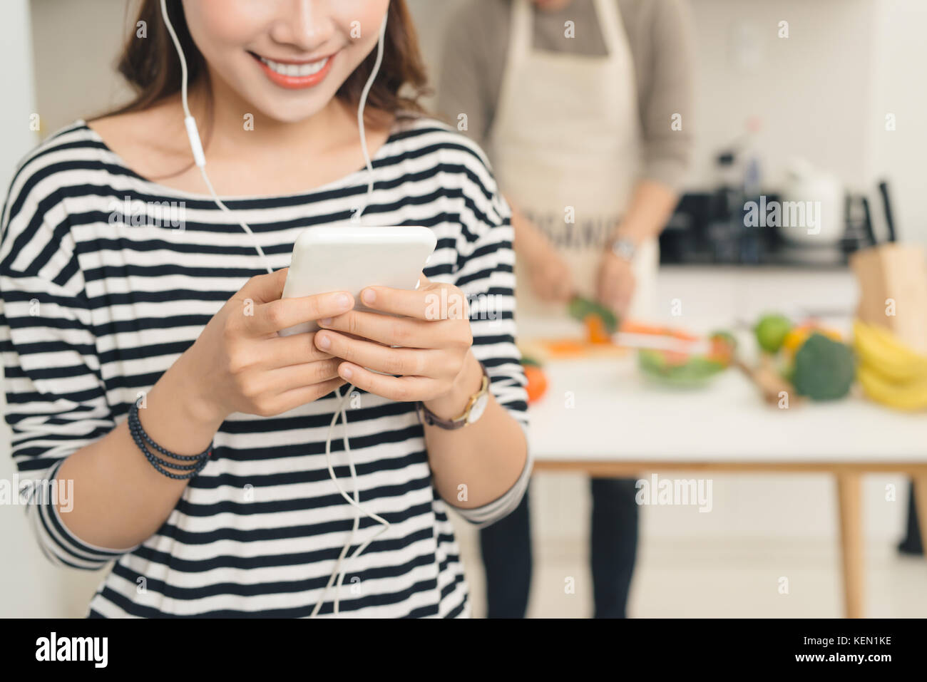 Smiling asian woman in the kitchen writing text message Stock Photo - Alamy
