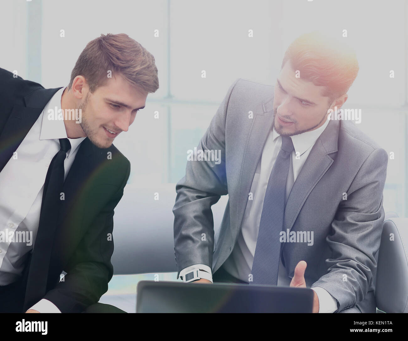 Smiling business men showing something on computer as colleague looking ...