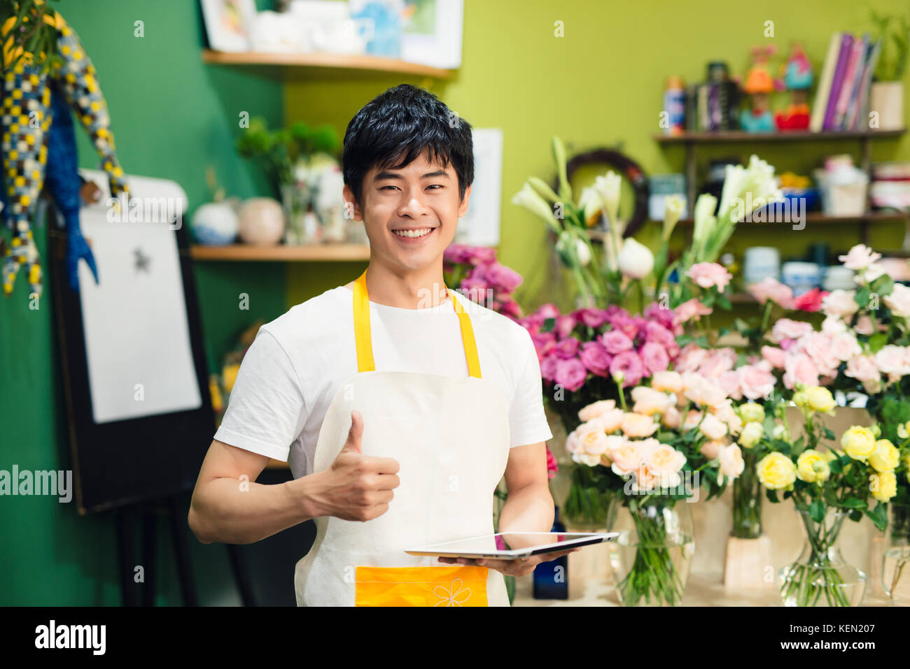 Cropped image of asian male florist making notes at flower shop counter ...