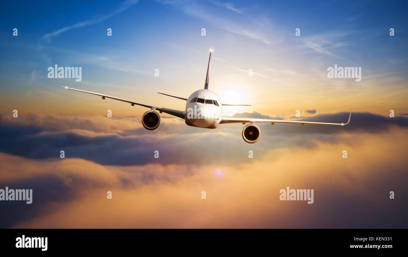 Commercial airplane flying above clouds in dramatic sunset light. High ...