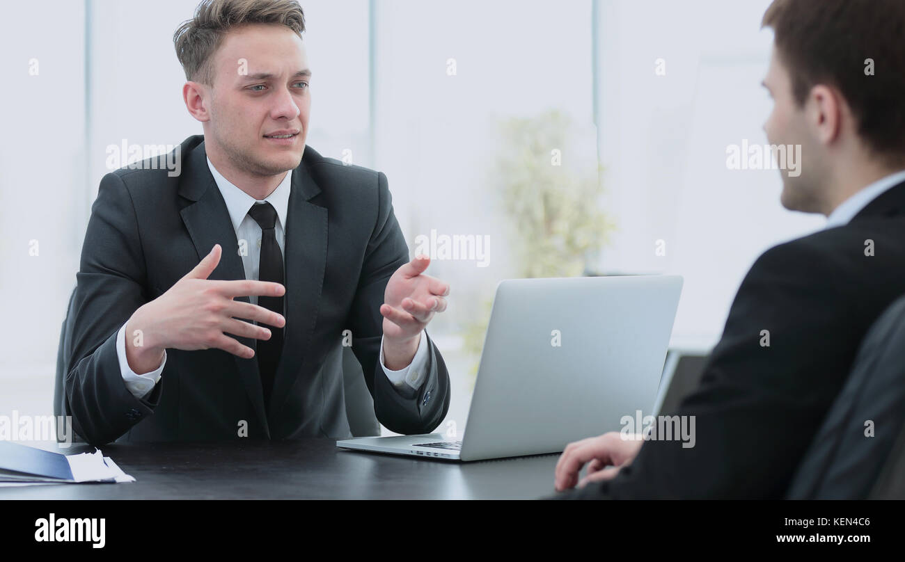 Bank employee sitting behind a Desk and talks to the client Stock Photo ...