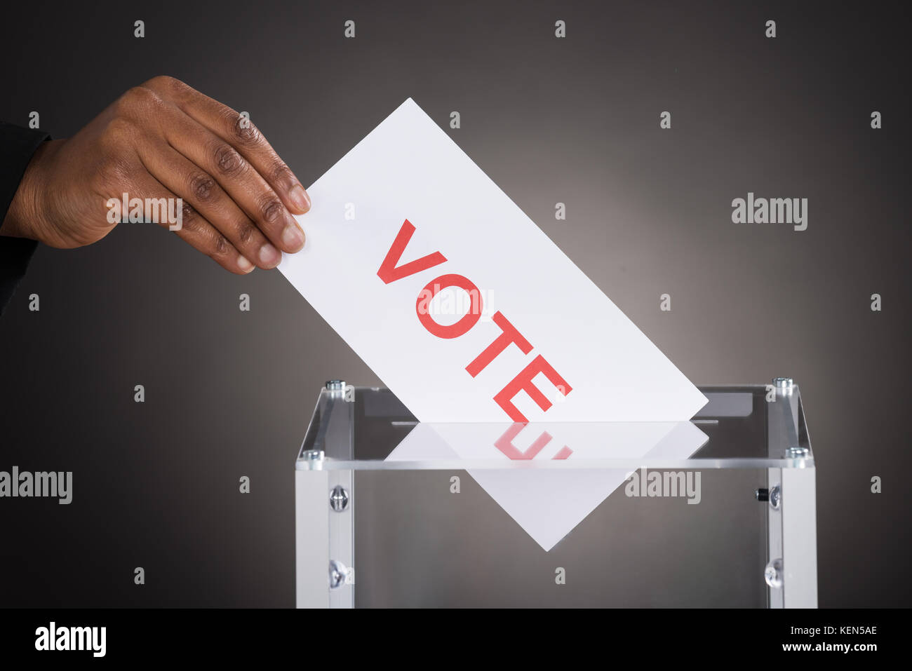 Close-up Of A Person Hand Putting Vote In A Ballot Box Against Gray ...