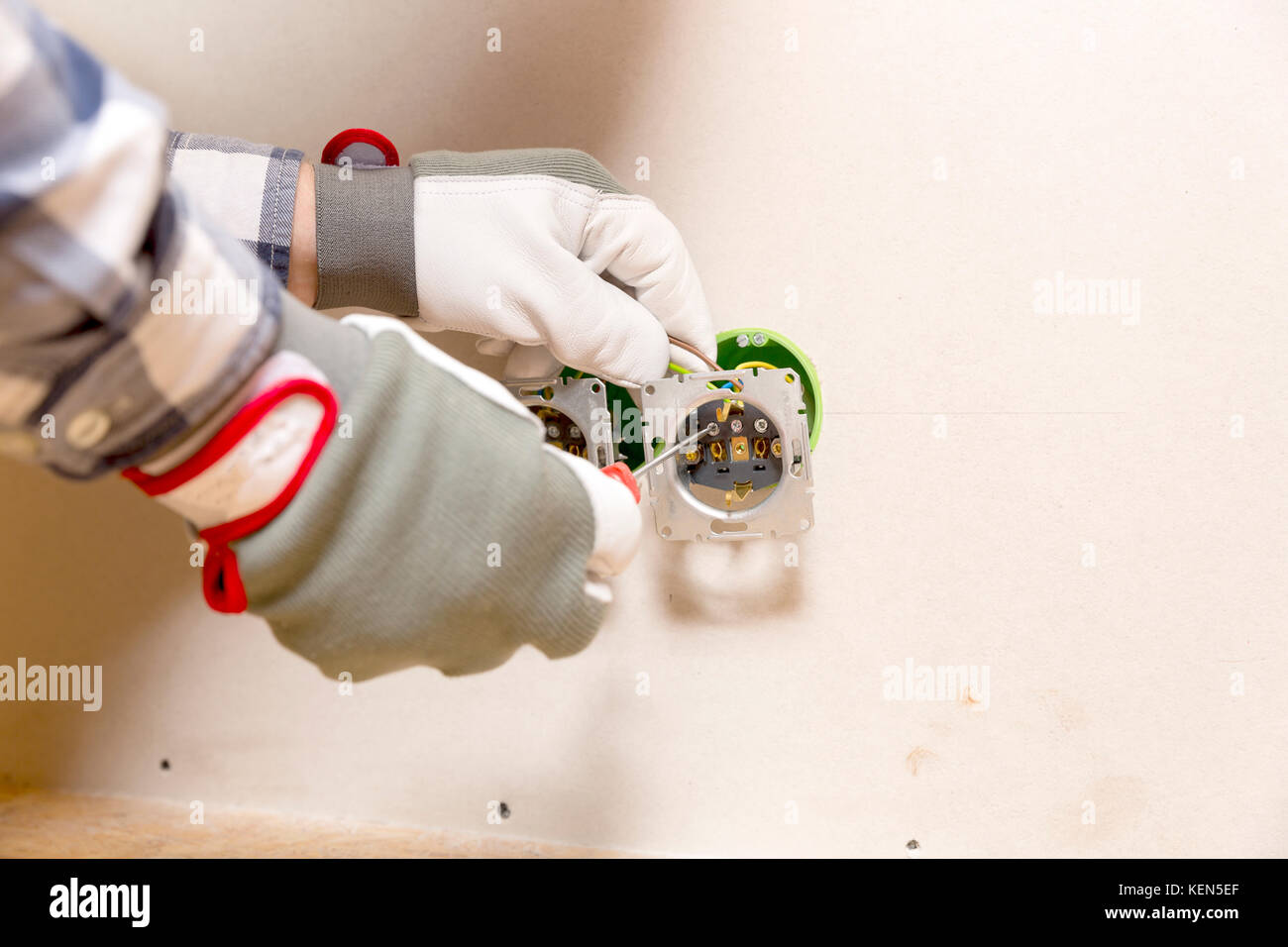 Hands of electrician installing socket in gypsum wall Stock Photo - Alamy