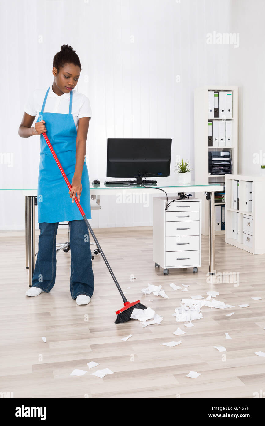 Young Female Janitor Sweeping Torn Paper Pieces On Hardwood Floor Stock ...