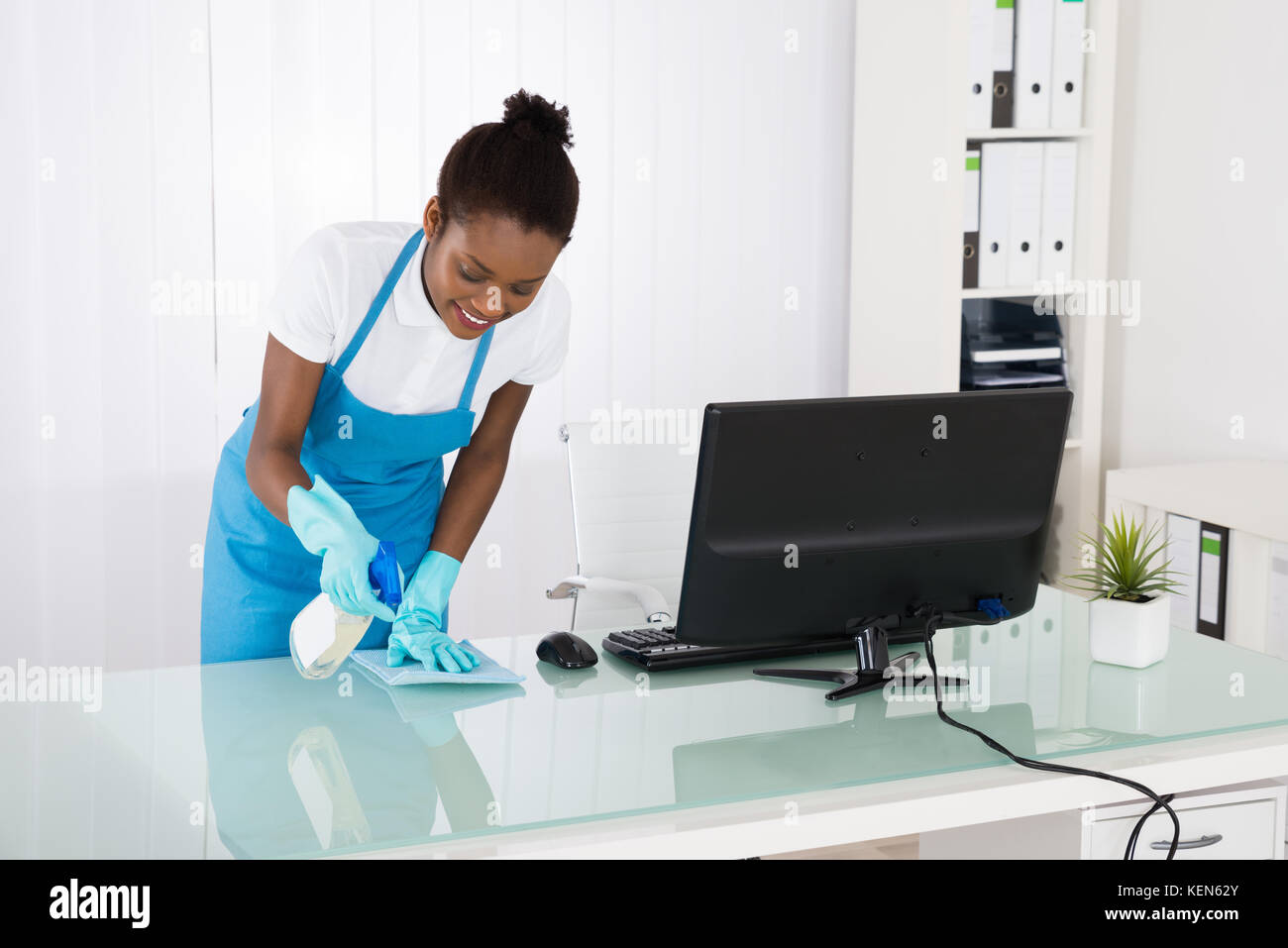 Happy Young African Female Janitor Cleaning Desk With Rag In Office ...