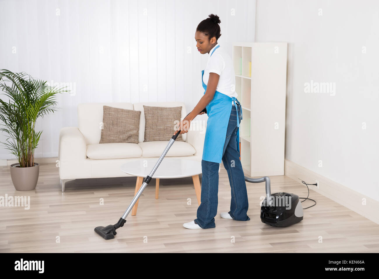 Young Female Janitor Cleaning Floor With Vacuum Cleaner In Room Stock ...