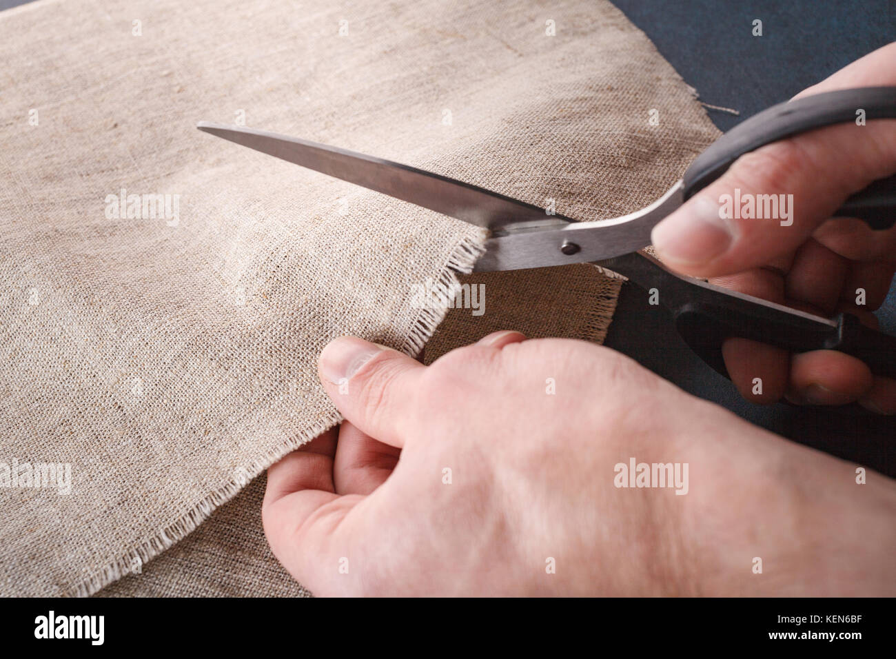 A man's hand cuts linen cloth with tailor's scissors Stock Photo - Alamy